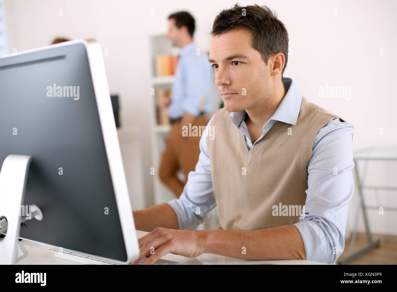 Man working in office in front of desktop computer Stock Photo - Alamy
