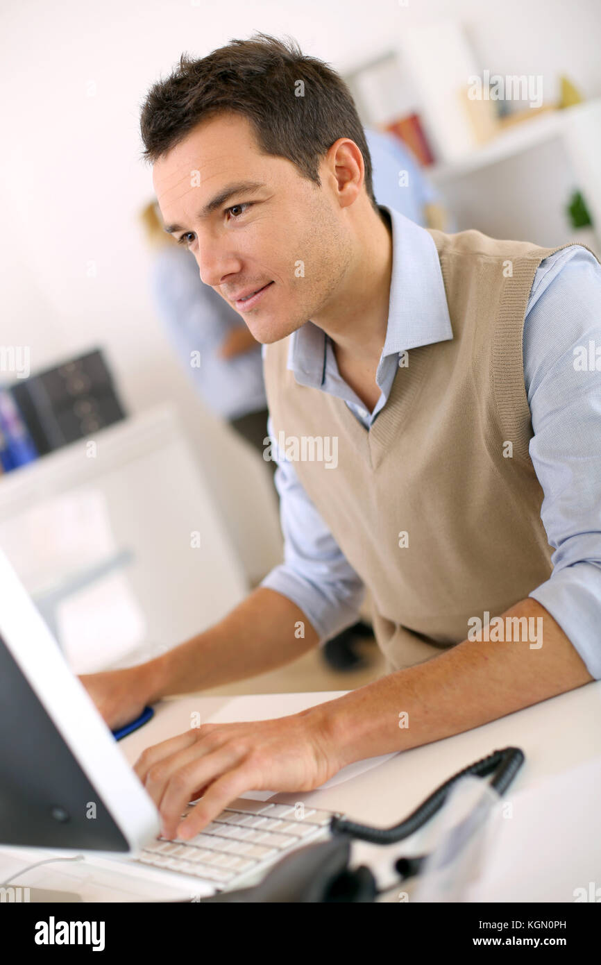 Man working in office in front of desktop computer Stock Photo - Alamy