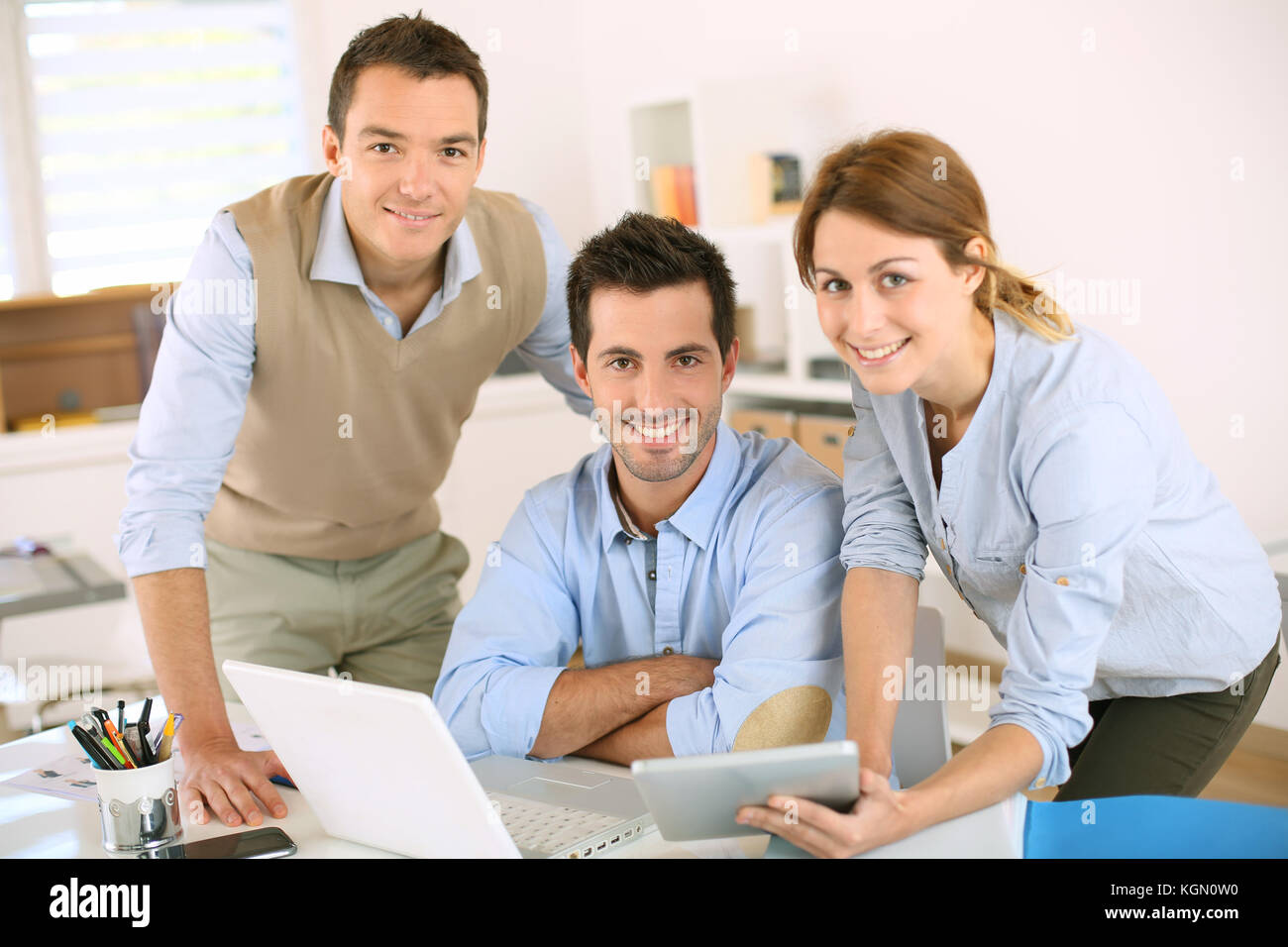 Smiling business team looking at camera Stock Photo - Alamy