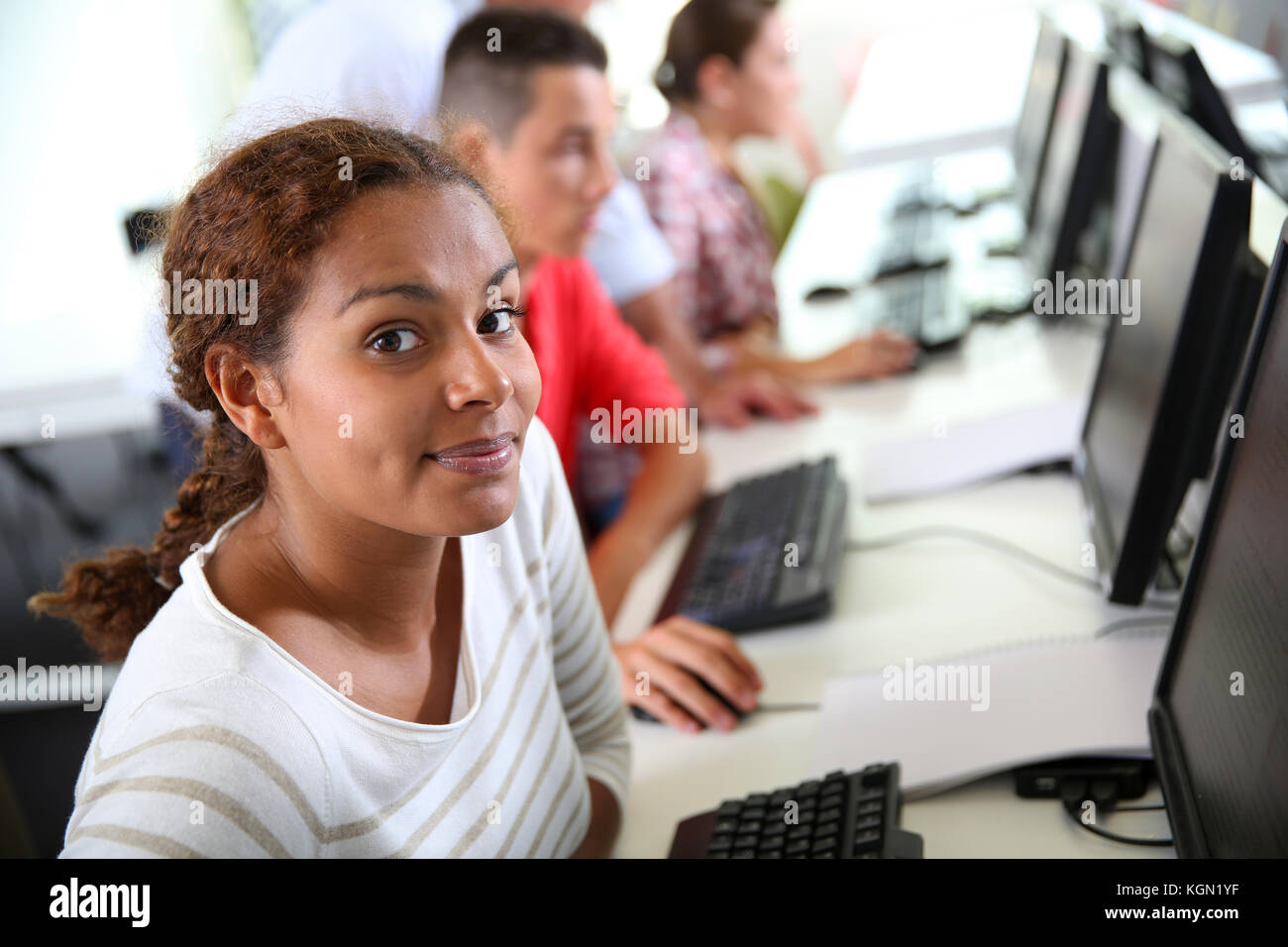 Smiling student girl sitting in computing class Stock Photo - Alamy