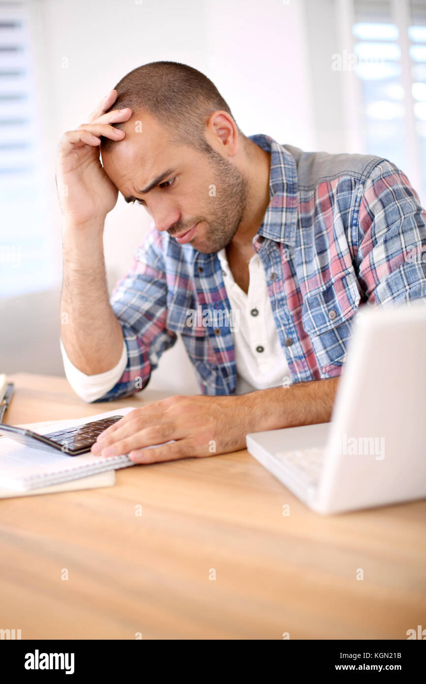 Young man being worried at looking at bank accounts Stock Photo - Alamy