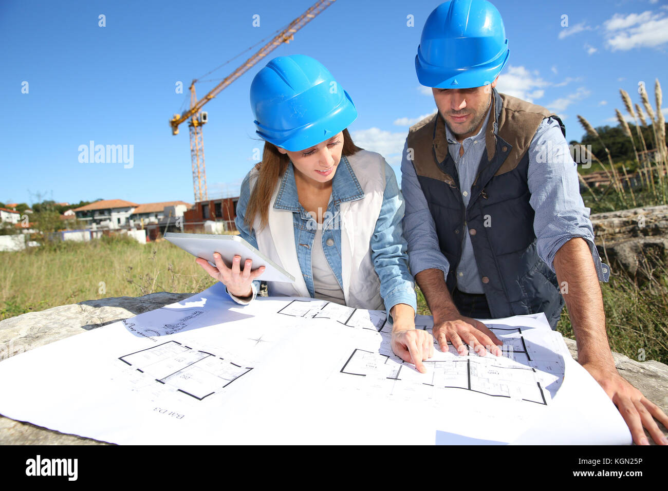 Construction people looking at blueprint Stock Photo - Alamy