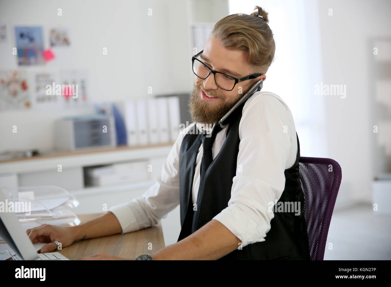 Young designer in office talking on phone Stock Photo - Alamy