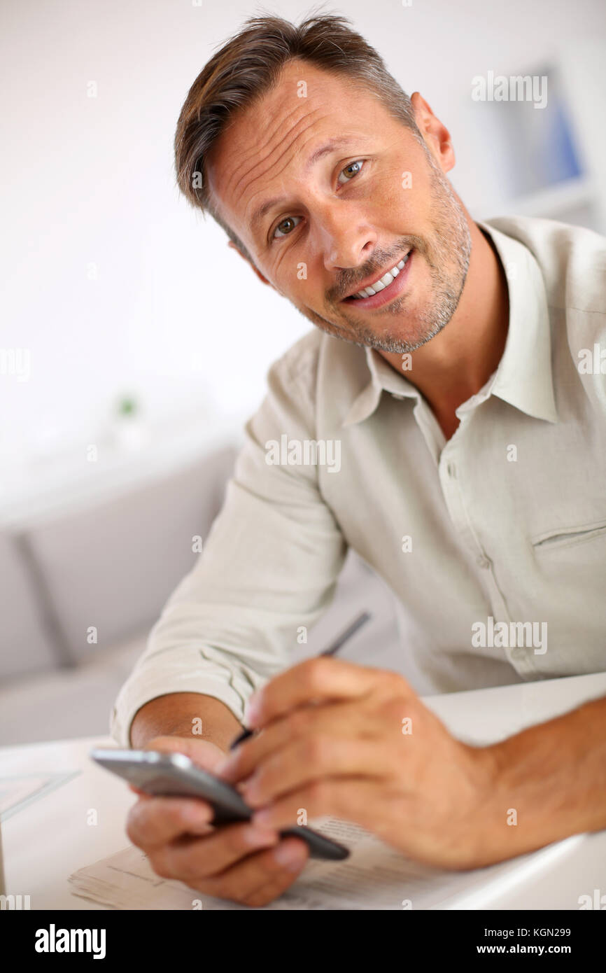 Smiling guy sending message with smartphone Stock Photo - Alamy