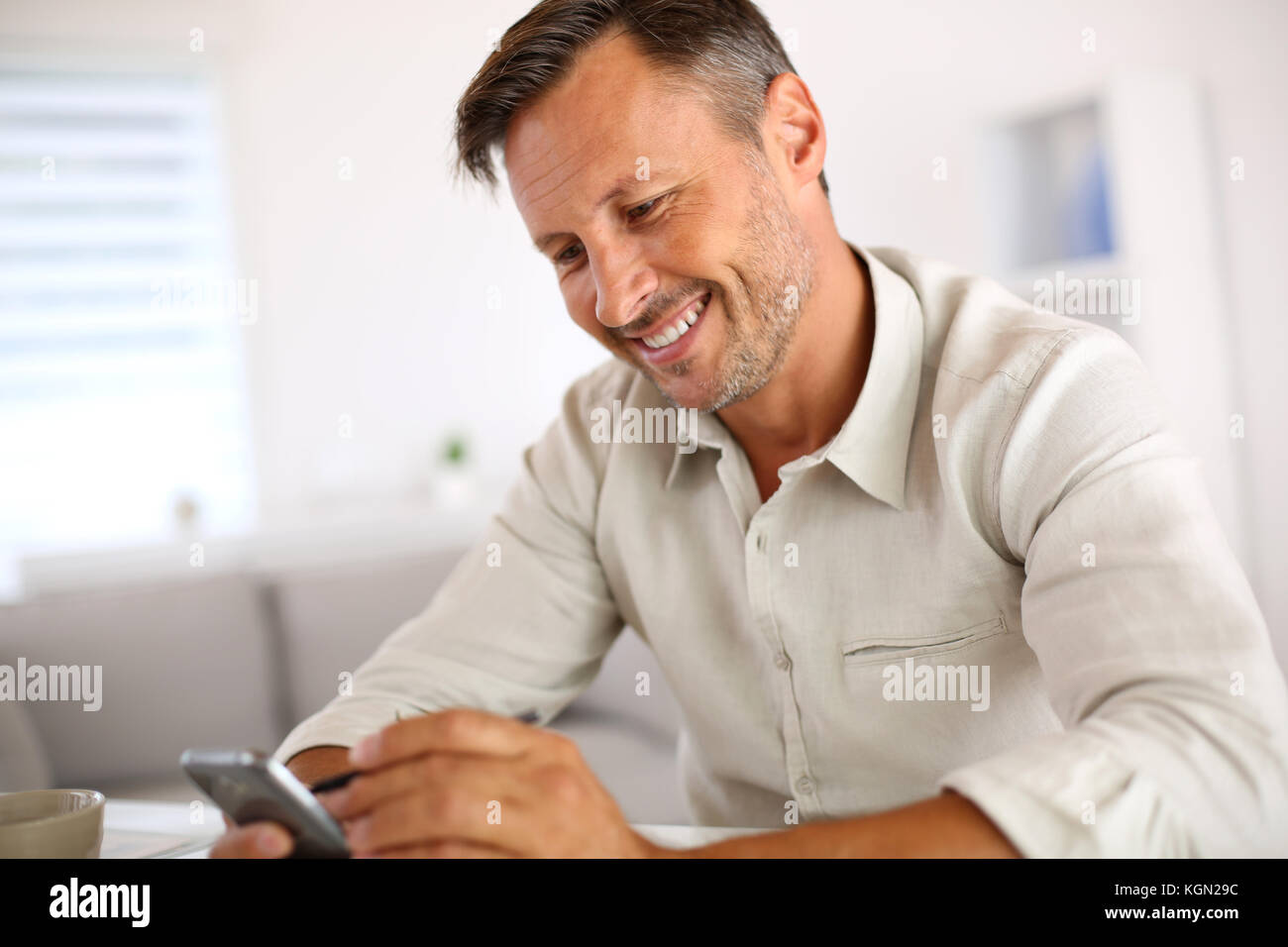 Smiling guy sending message with smartphone Stock Photo - Alamy