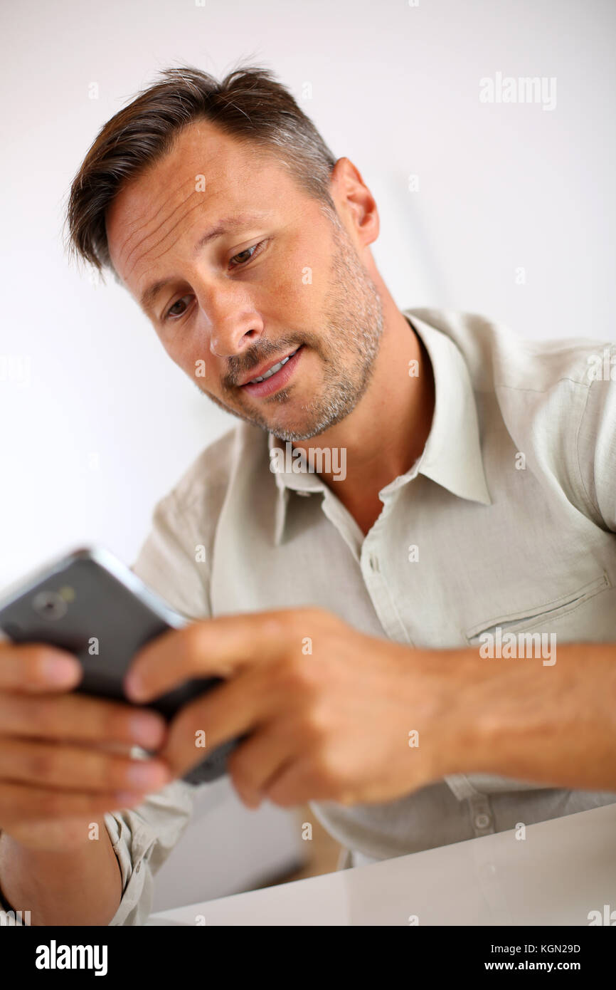 Smiling guy sending message with smartphone Stock Photo - Alamy