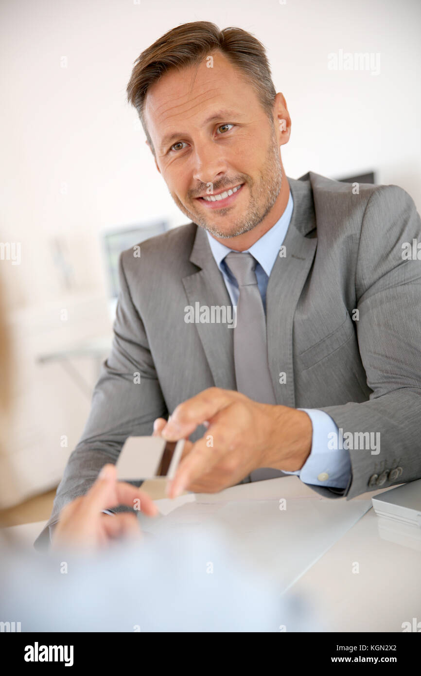 Banker giving credit card to client Stock Photo - Alamy