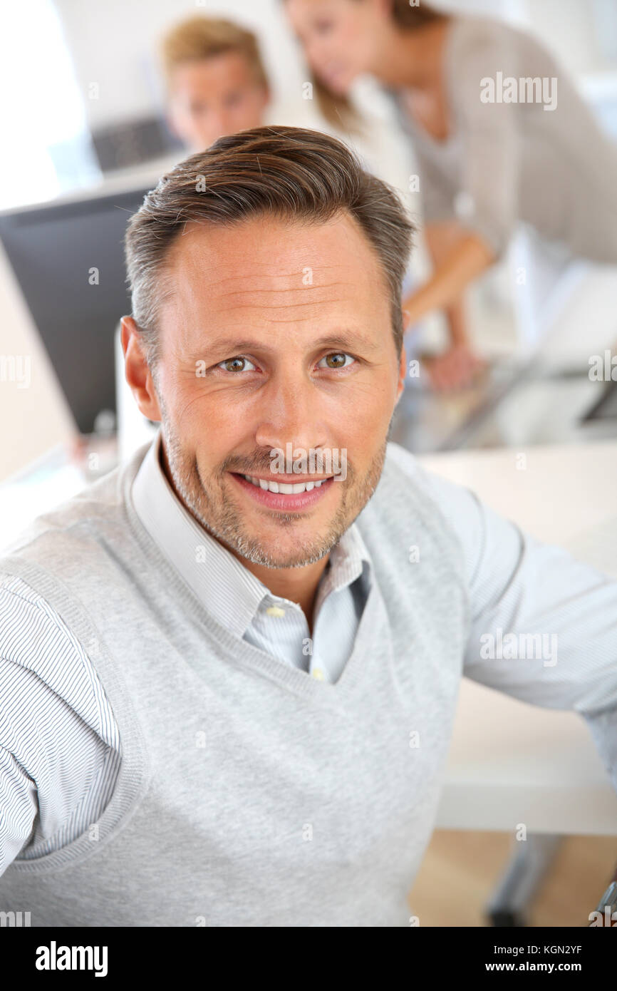 Cheerful man sitting in office and working on desktop Stock Photo - Alamy