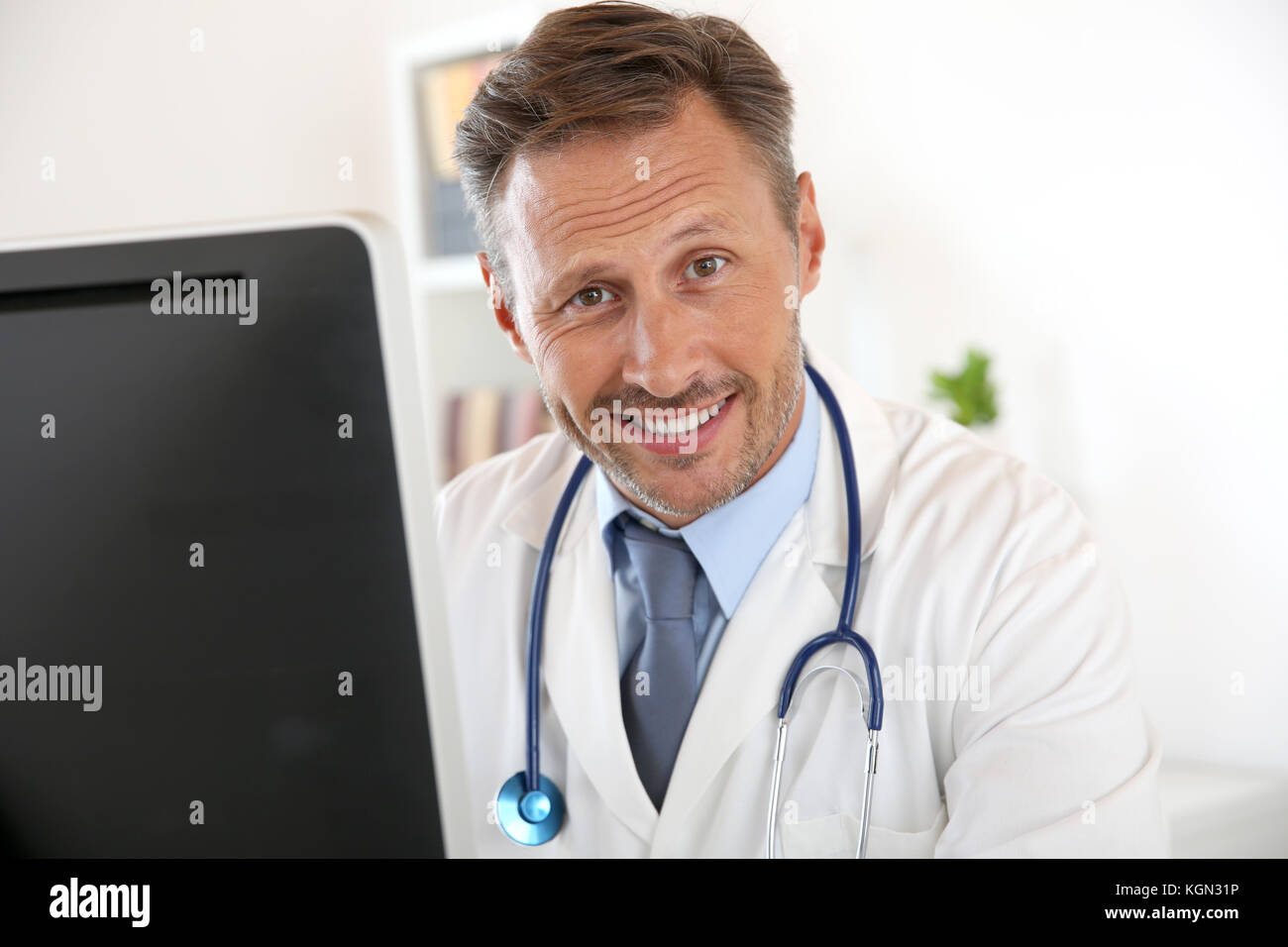 Portrait of doctor sitting in front of computer Stock Photo - Alamy