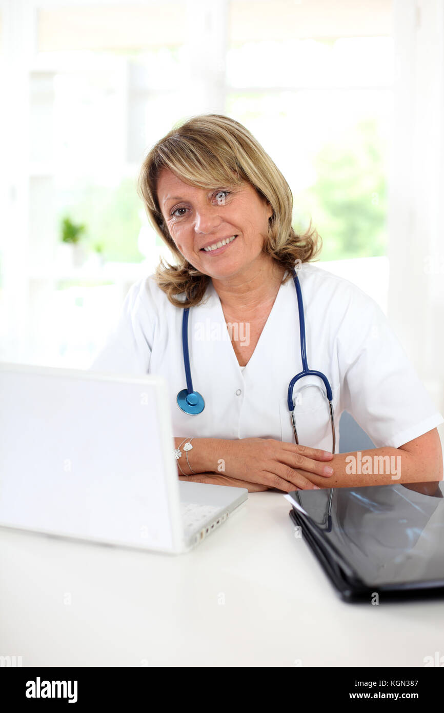 Portrait of mature nurse sitting at her desk Stock Photo - Alamy