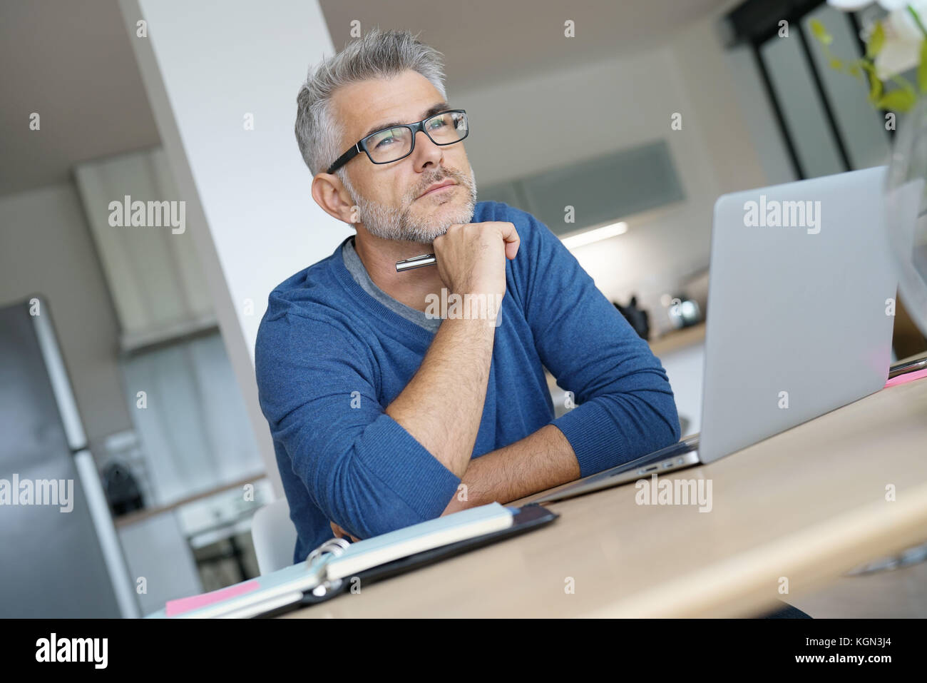 Middle-aged man working on laptop- thoughtful look Stock Photo - Alamy