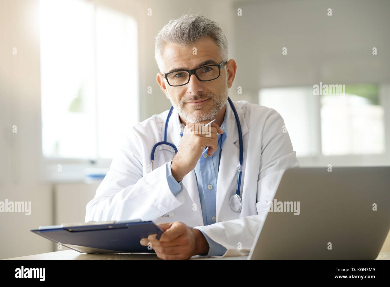 Doctor in office working on patient file Stock Photo - Alamy