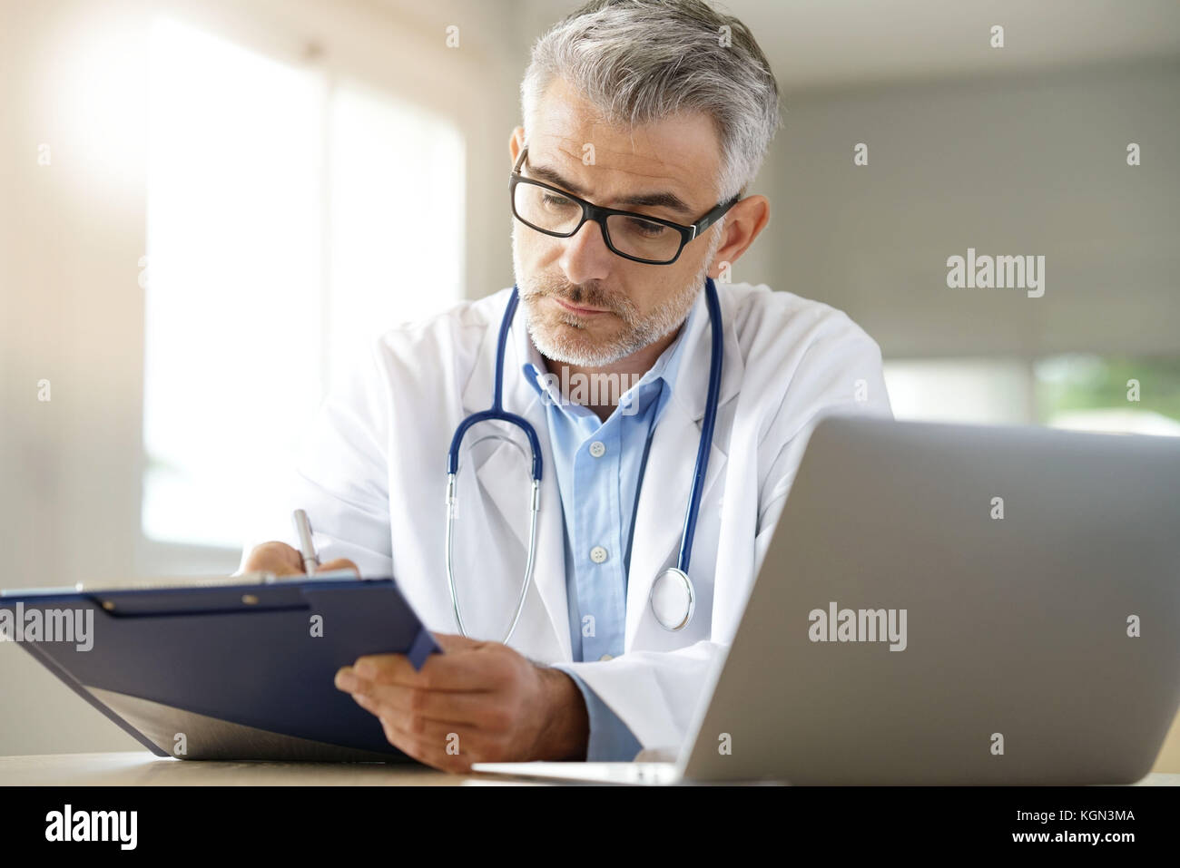 Doctor in office working on patient file Stock Photo - Alamy