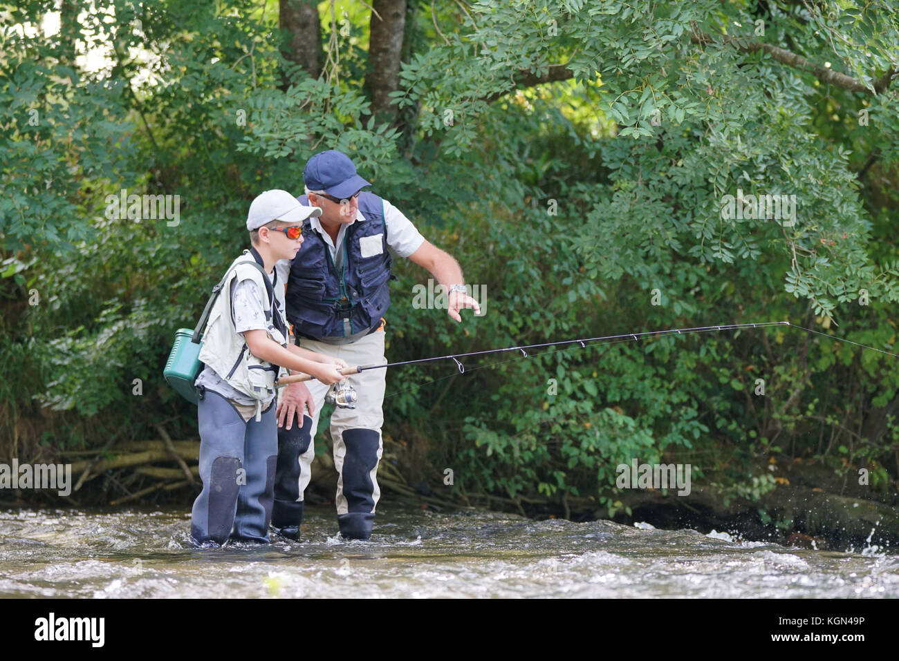Man teaching son how to fish in river Stock Photo - Alamy