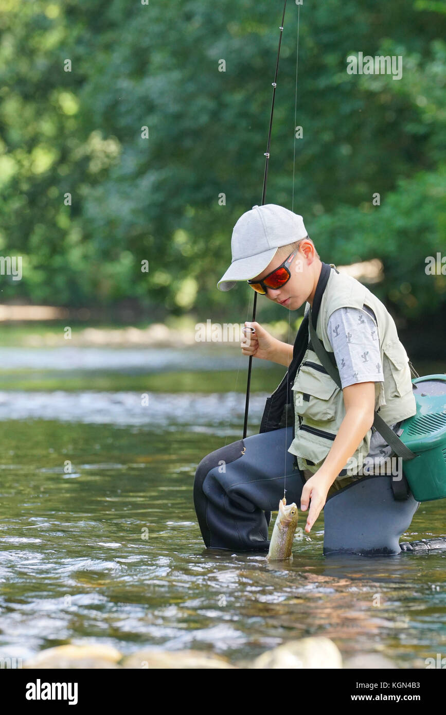 Young boy catching rainbow trout in river Stock Photo - Alamy