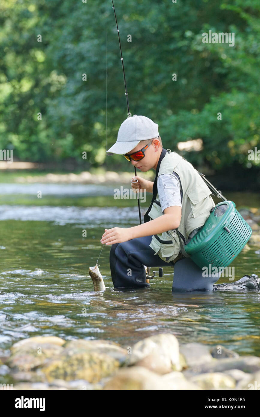 Young boy catching rainbow trout in river Stock Photo - Alamy