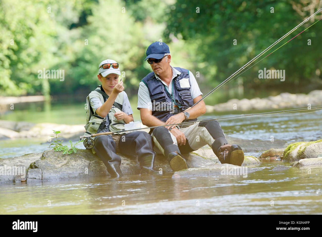 Father and son fly-fishing in river, sitting on rocks Stock Photo - Alamy