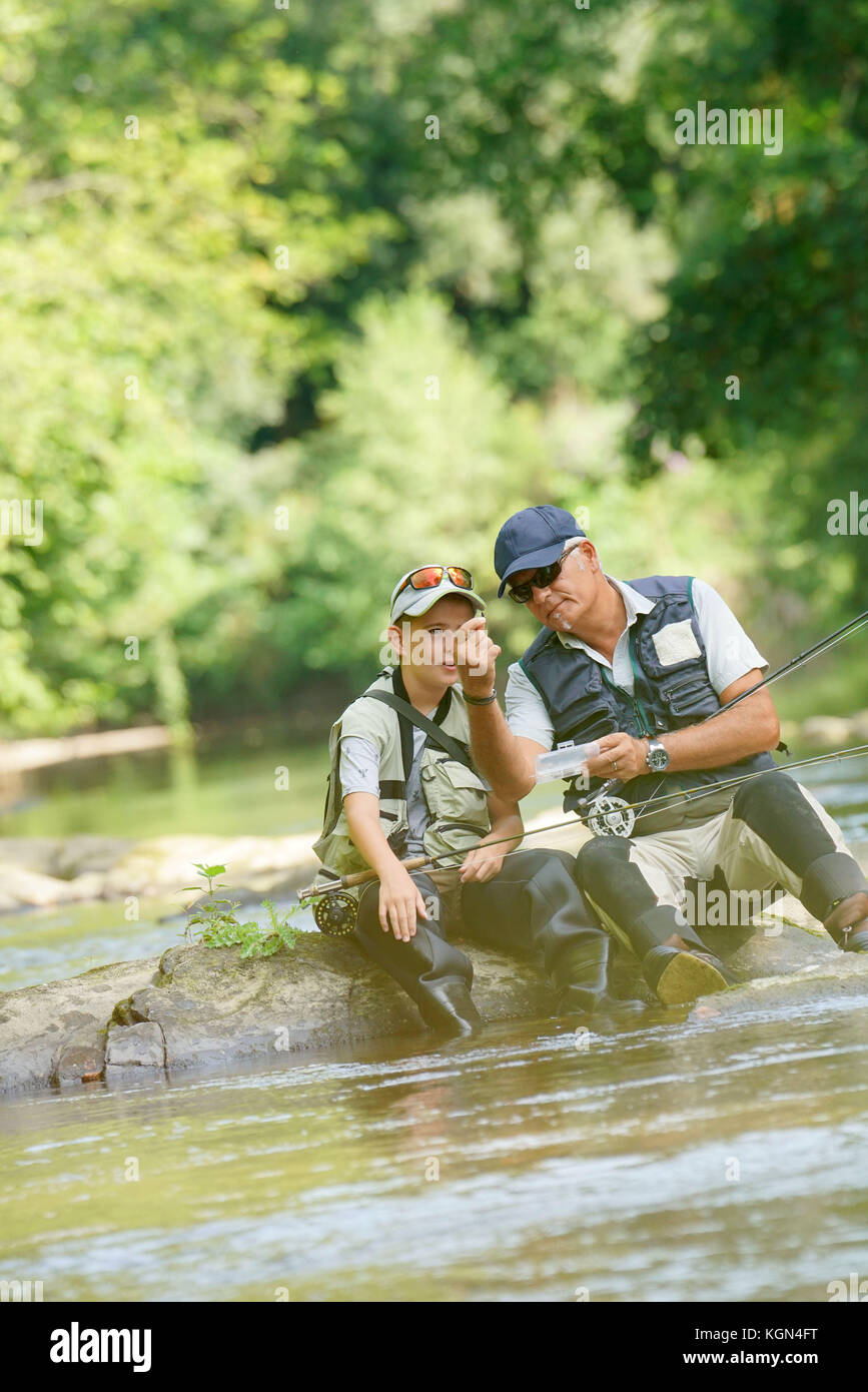 Father and son fly-fishing in river, sitting on rocks Stock Photo - Alamy