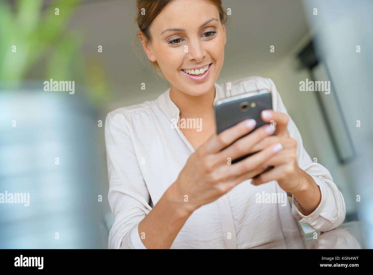 Cheerful woman sending message with smartphone Stock Photo - Alamy