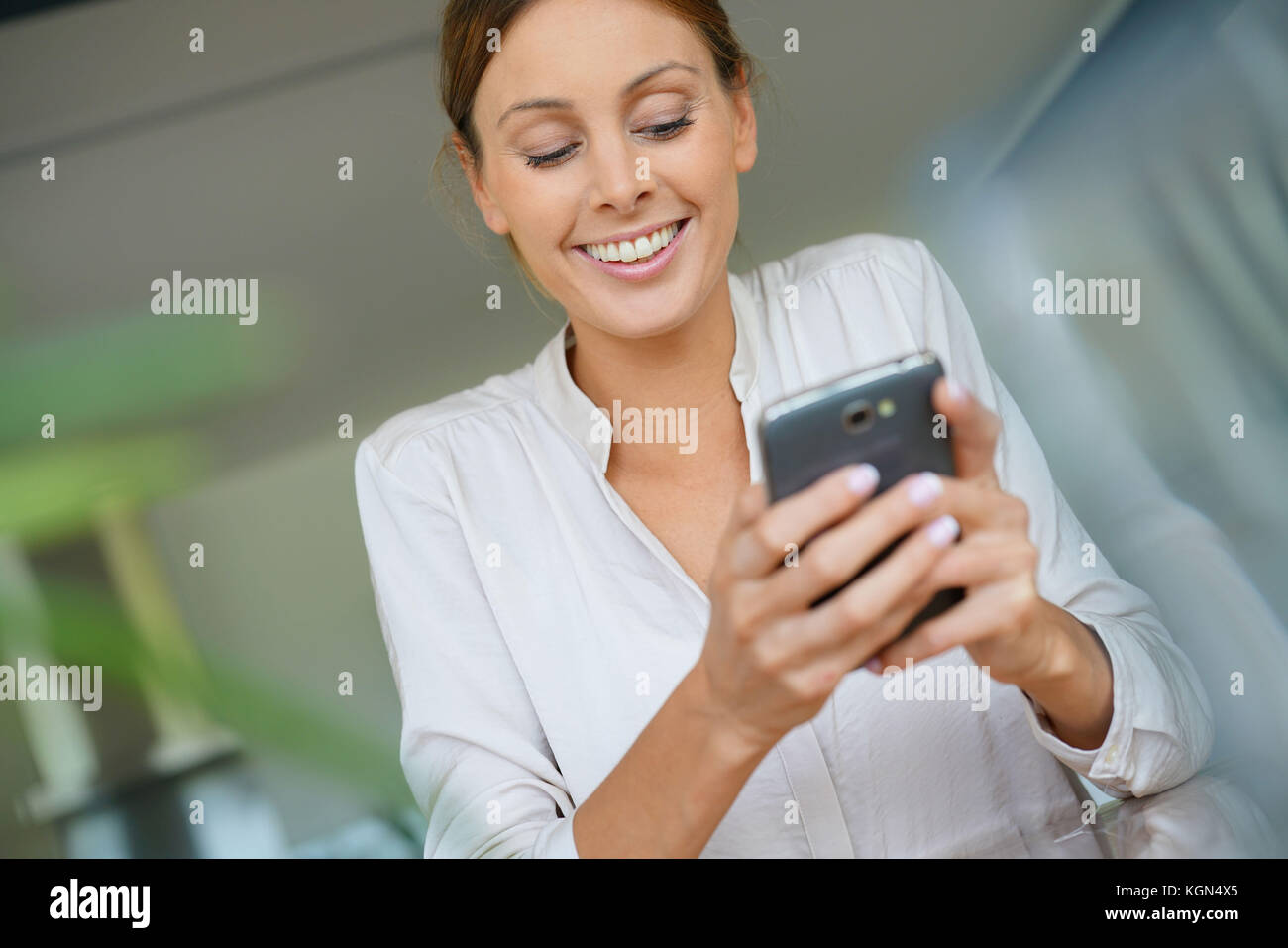 Cheerful woman sending message with smartphone Stock Photo - Alamy