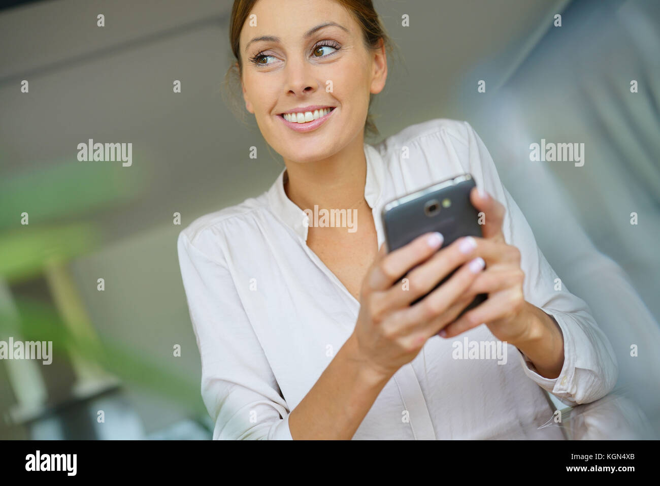 Cheerful woman sending message with smartphone Stock Photo - Alamy