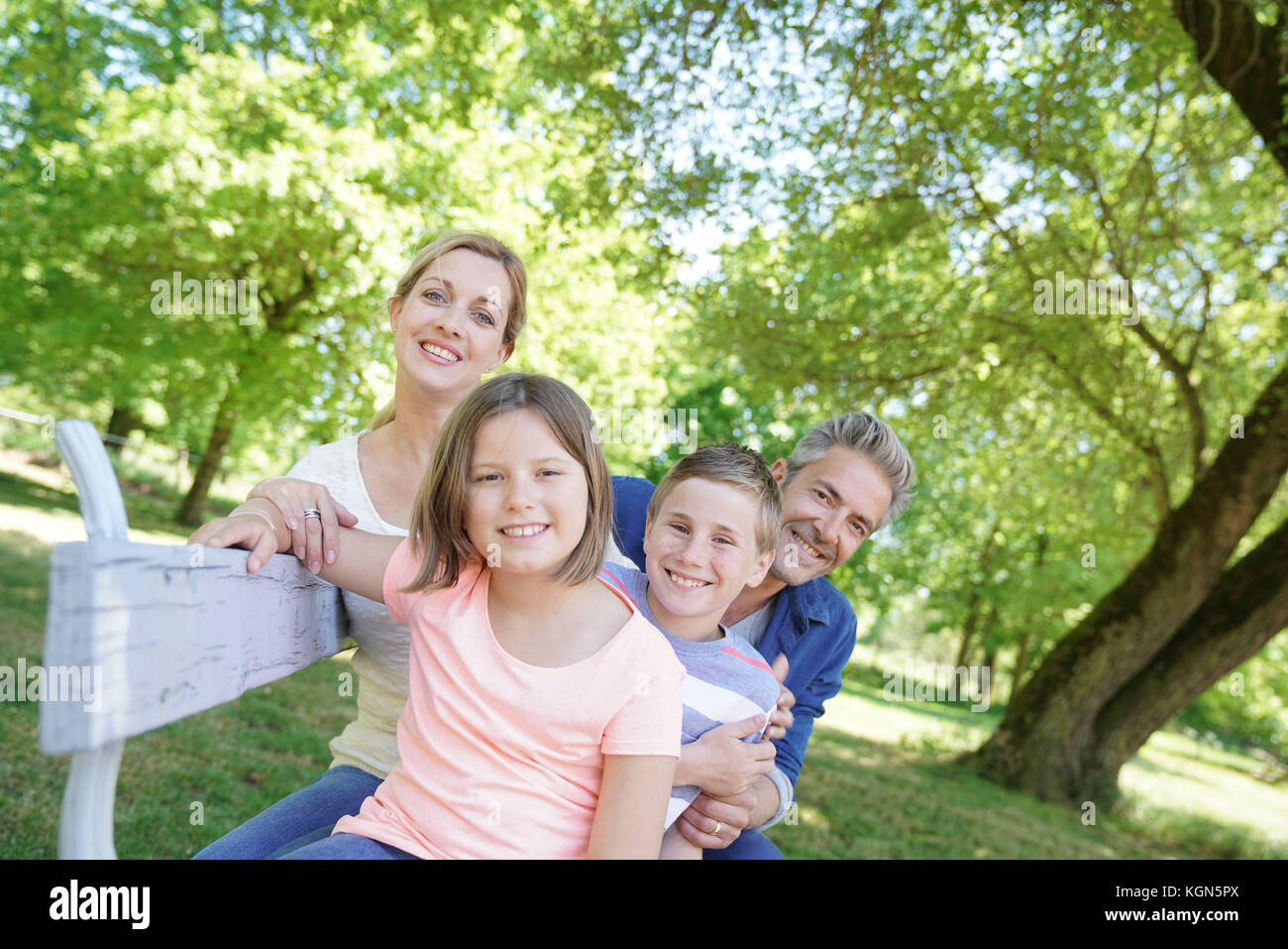 Happy family sitting on bench in park Stock Photo - Alamy