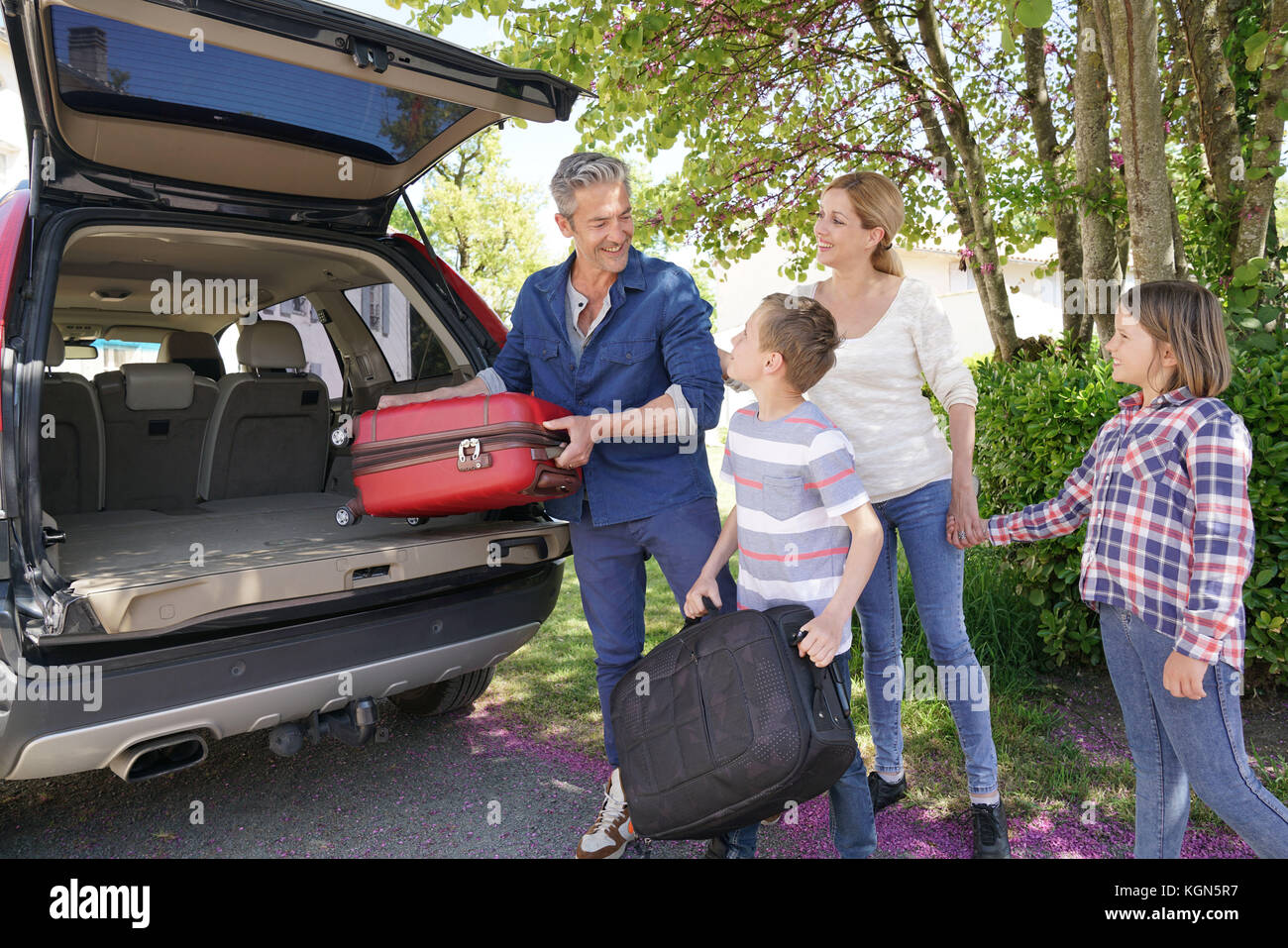 Happy family loading luggage in vehicle Stock Photo - Alamy