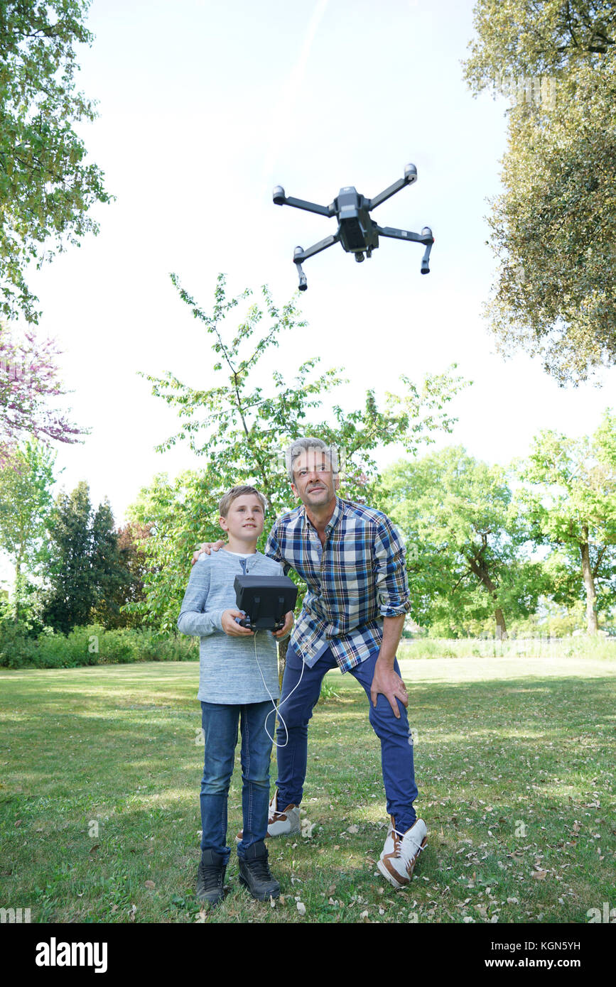 Father and son playing with flying drone in garden Stock Photo - Alamy
