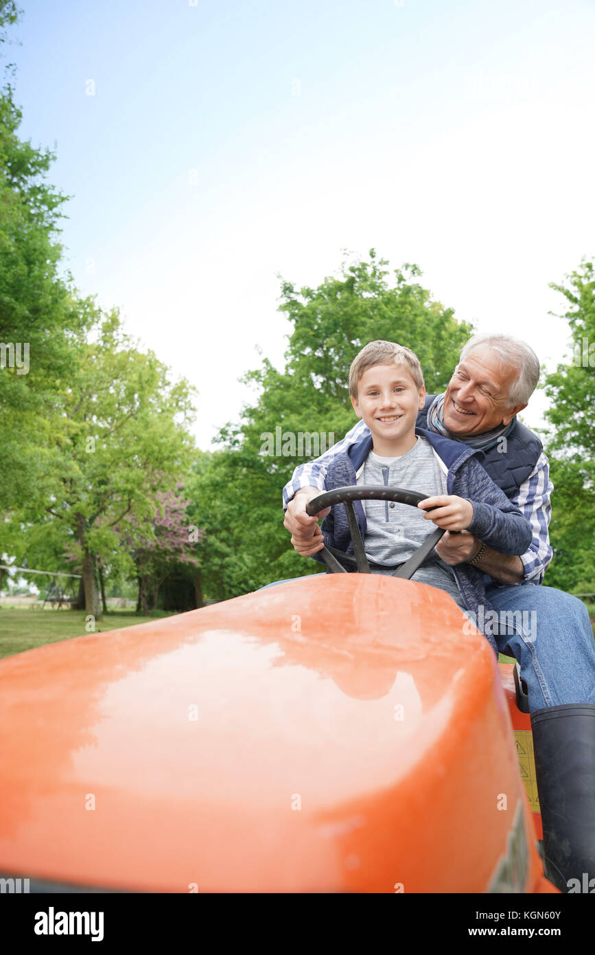 Senior man with grandkid riding on lawnmower Stock Photo - Alamy