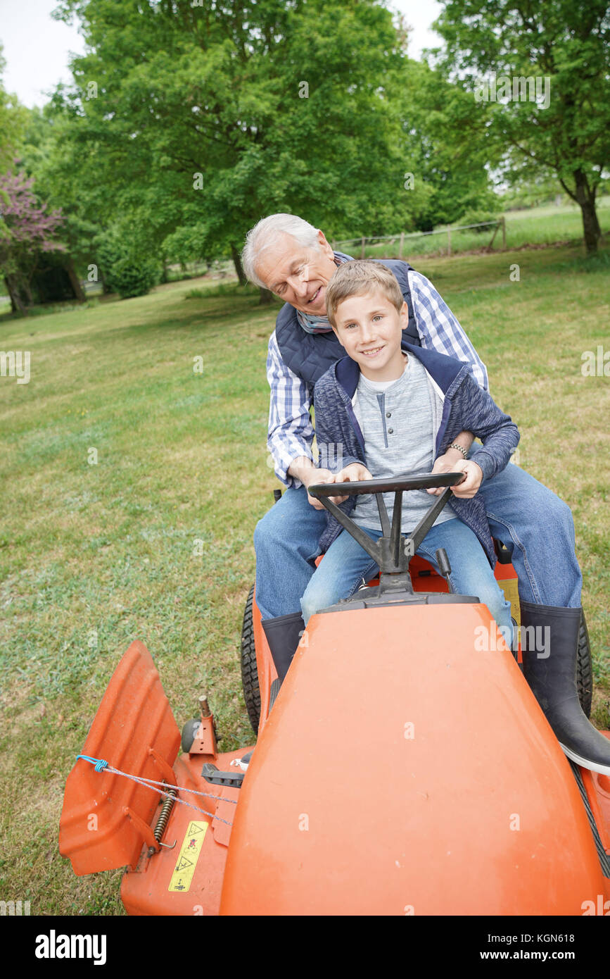 Senior man with grandkid riding on lawnmower Stock Photo - Alamy
