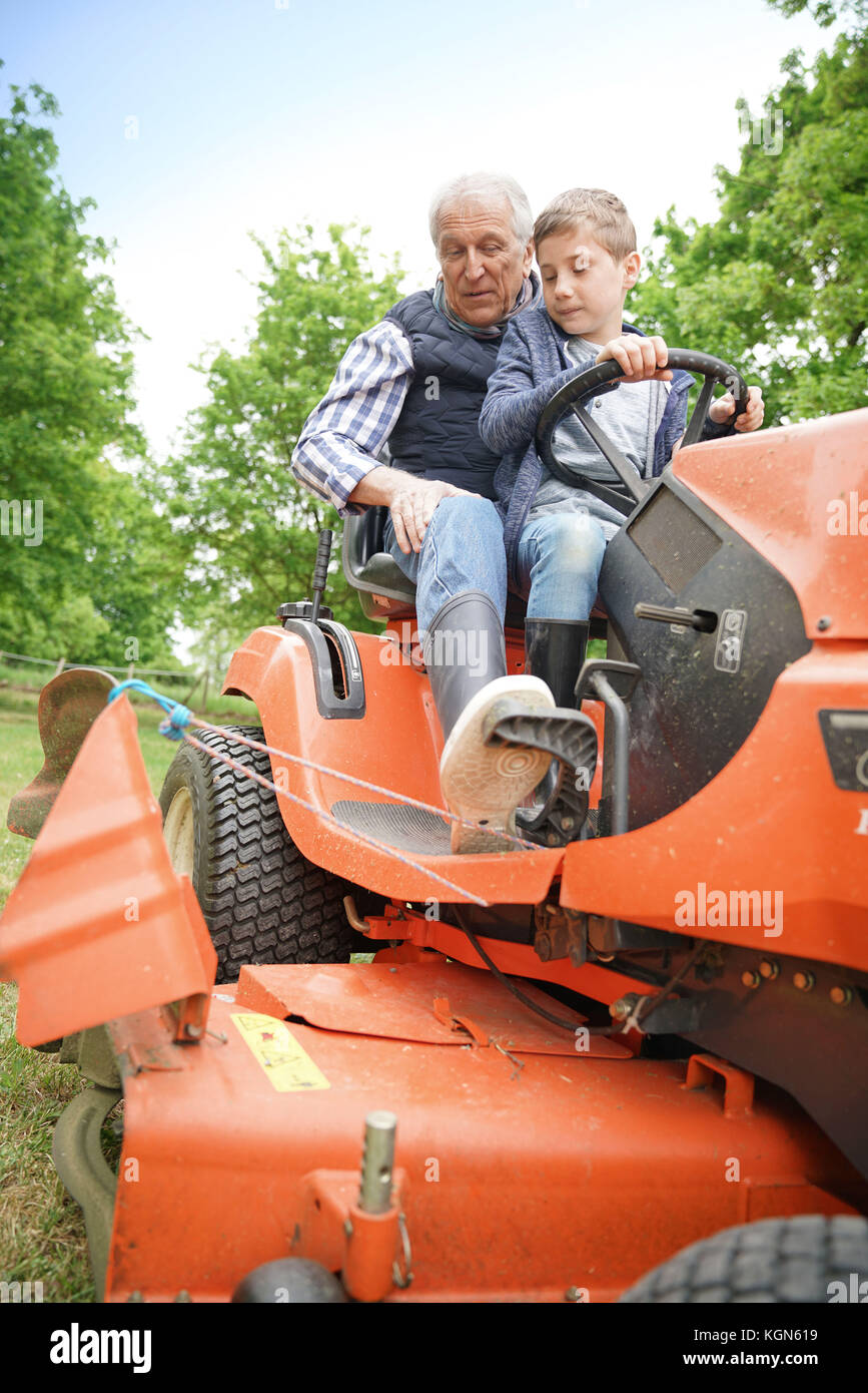 Senior man with grandkid riding on lawnmower Stock Photo - Alamy