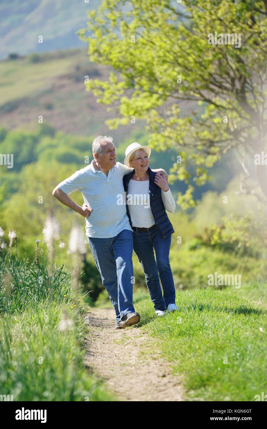 Senior couple walking in country track by sunny day Stock Photo - Alamy
