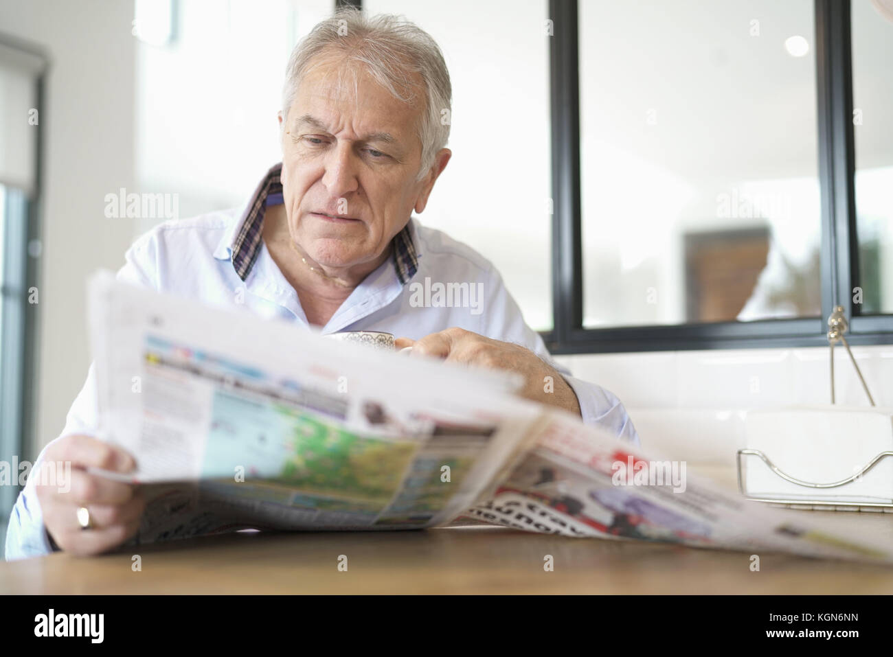 Senior man at home reading newspaper Stock Photo - Alamy