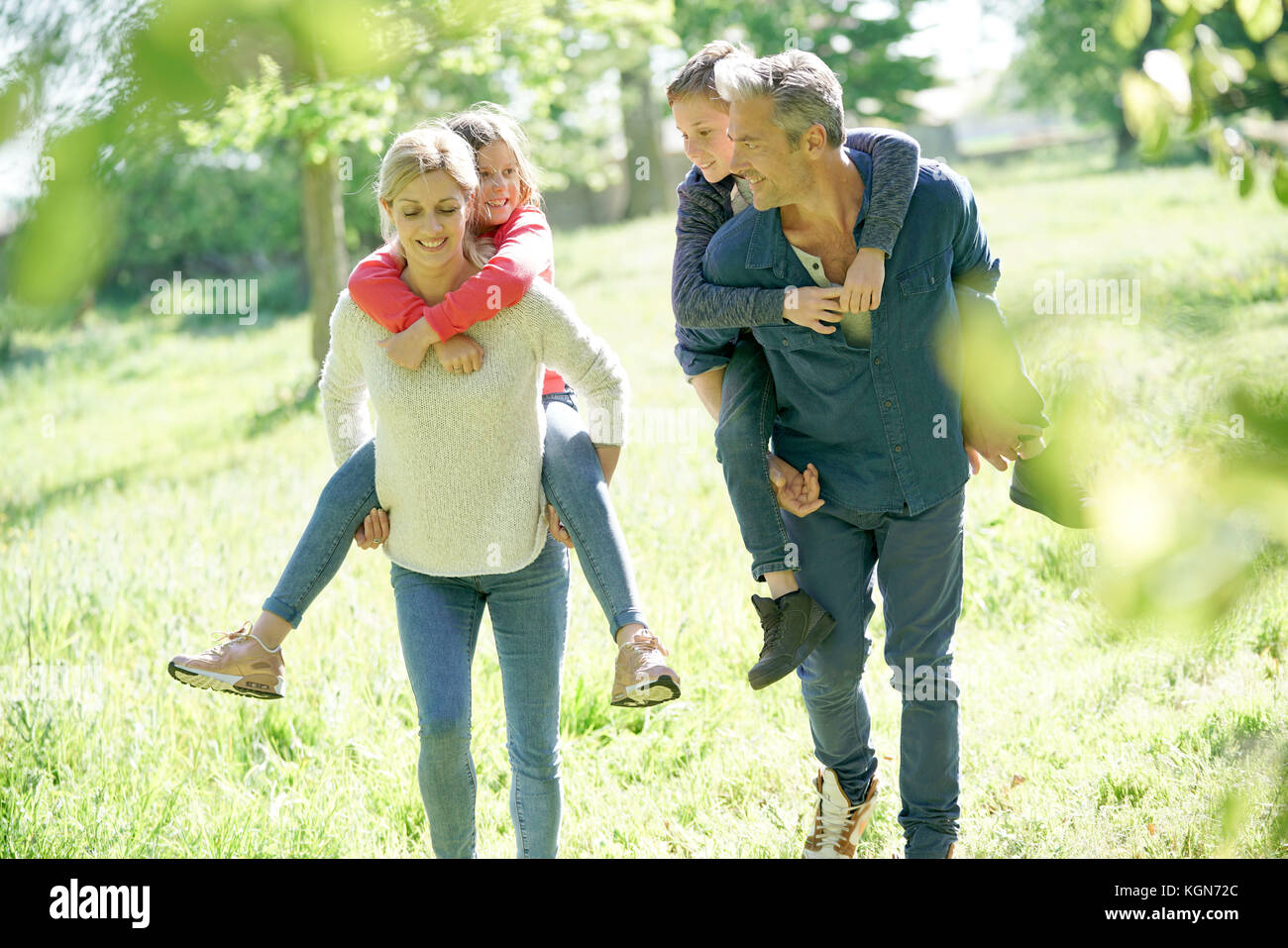 Parents giving piggyback ride to kids in countryside Stock Photo - Alamy