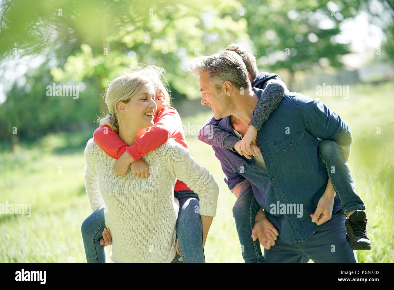Parents giving piggyback ride to kids in countryside Stock Photo - Alamy