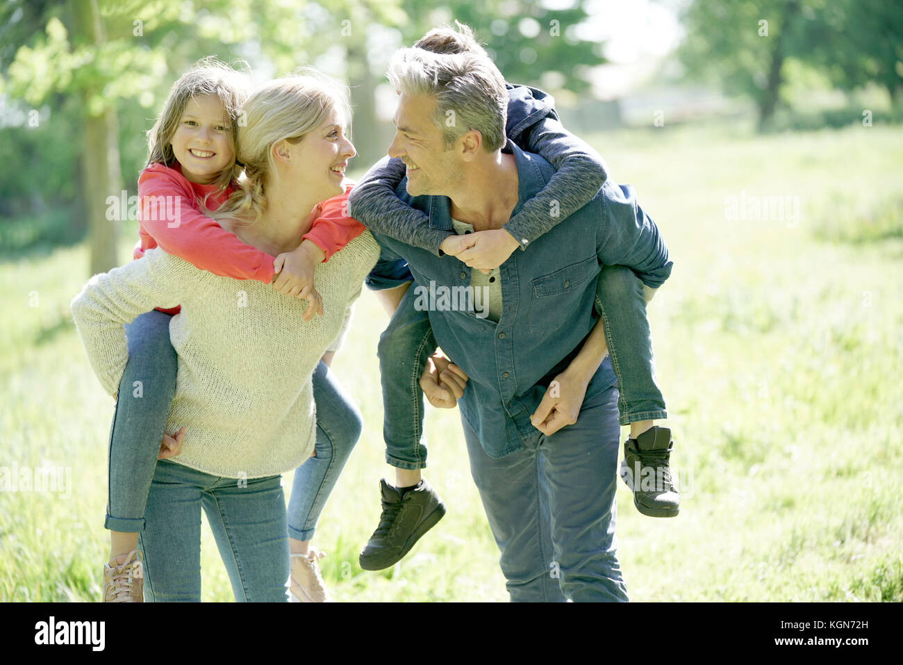 Parents giving piggyback ride to kids in countryside Stock Photo - Alamy