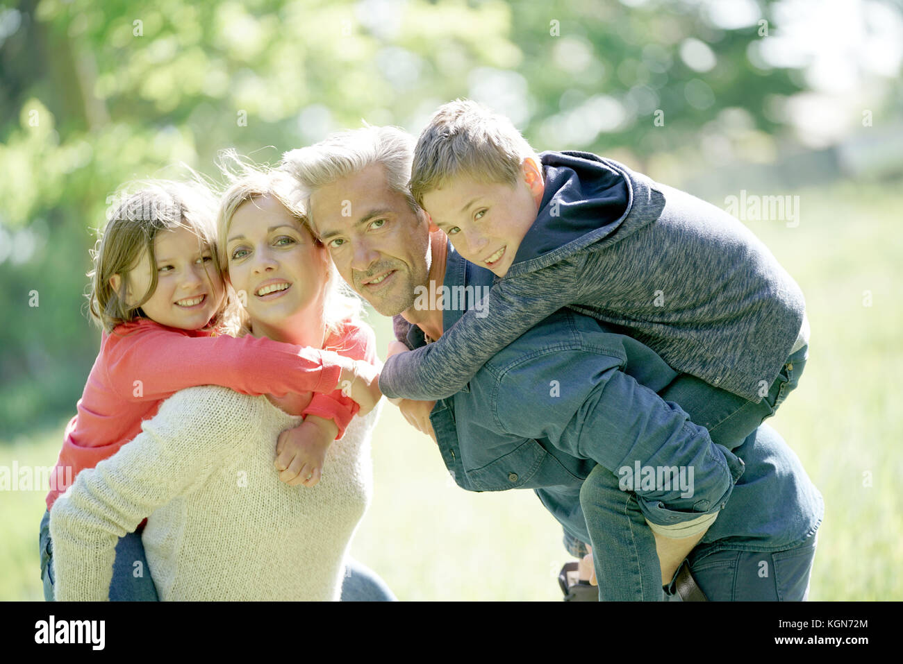 Parents giving piggyback ride to kids in countryside Stock Photo - Alamy