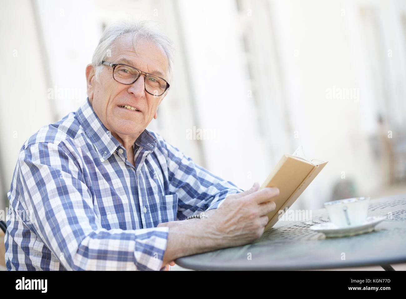 Elderly man with eyeglasses reading book outside Stock Photo - Alamy