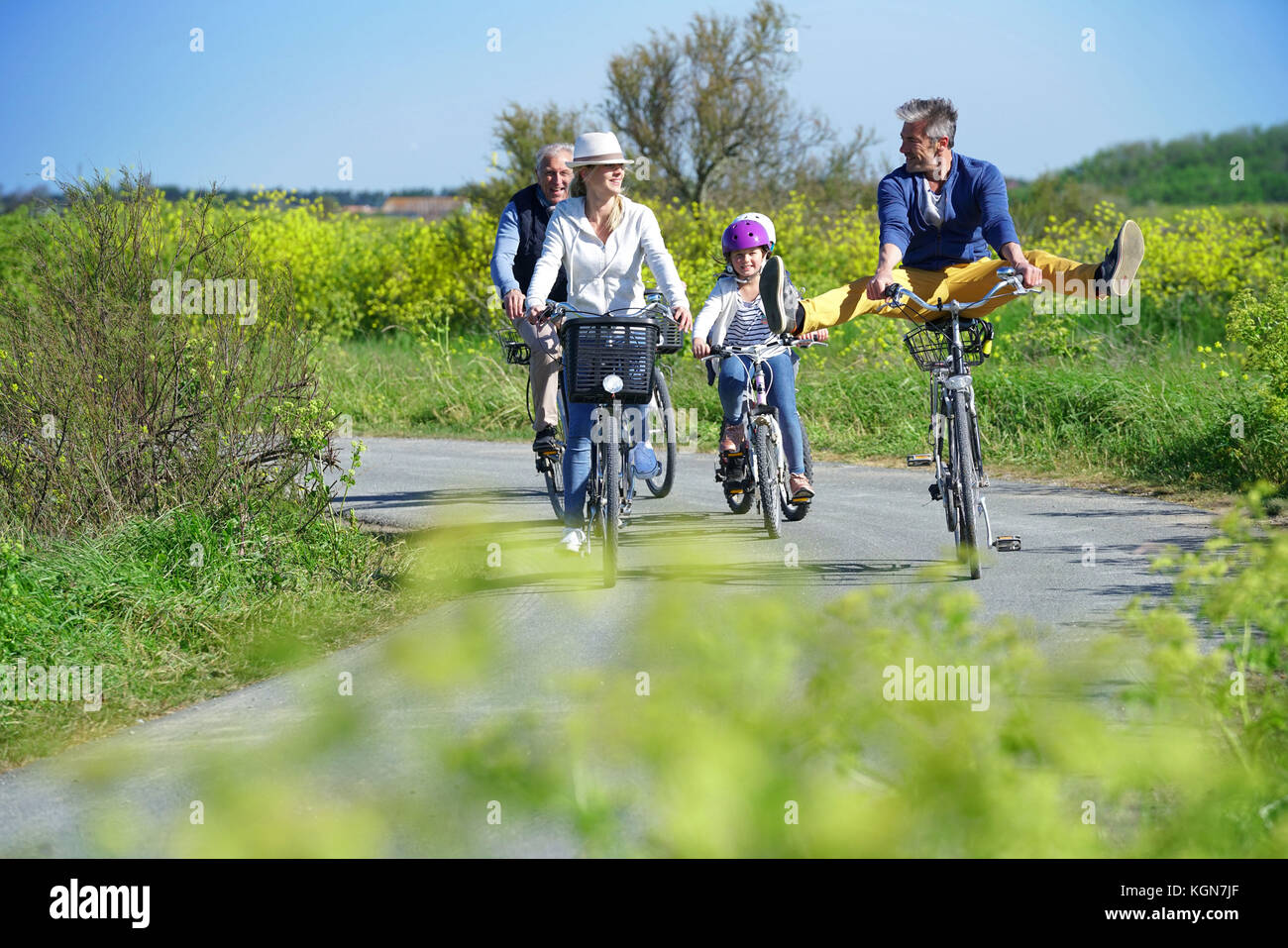 Family riding bikes together on country road Stock Photo - Alamy