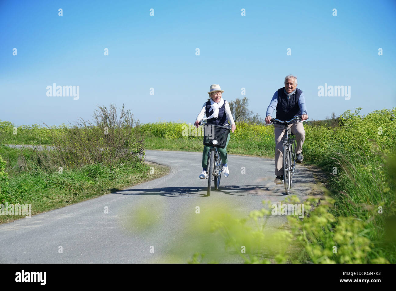 Senior couple riding bike together on country road Stock Photo - Alamy