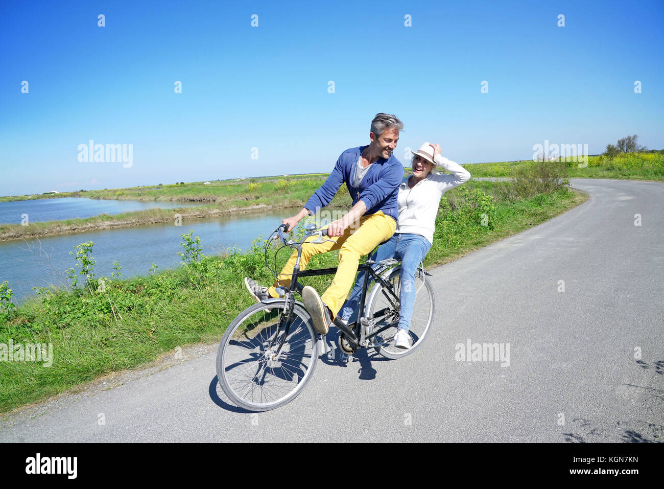 Cheerful couple riding bike on a sunny day Stock Photo - Alamy