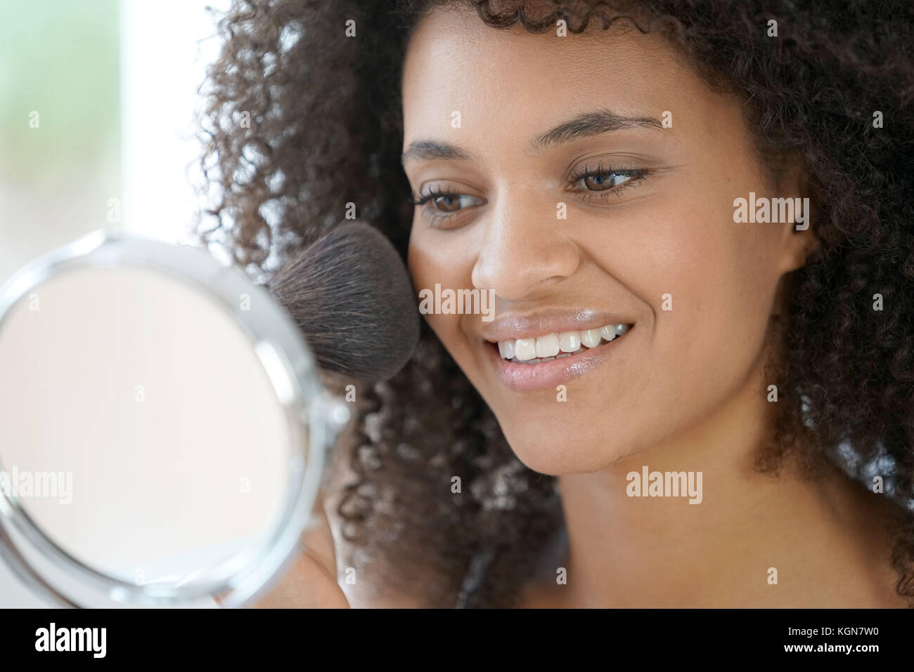 Beautiful mixed-race woman putting makeup on Stock Photo - Alamy