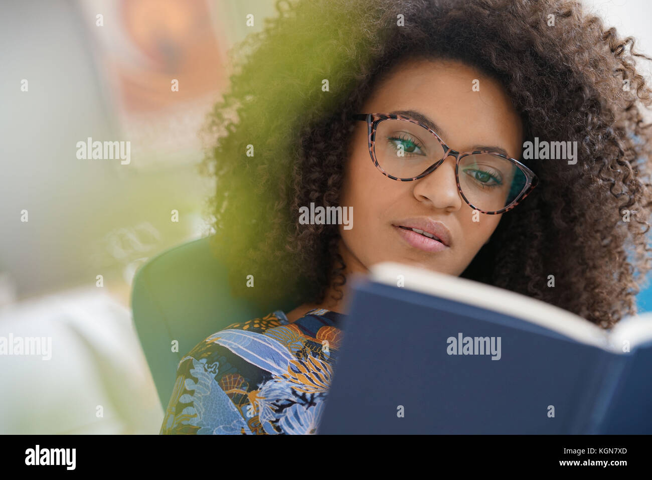 Mixed-race girl with eyeglasses reading book at home Stock Photo - Alamy