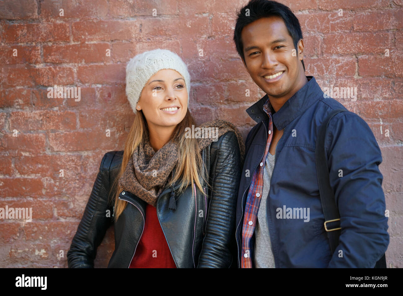 Trendy couple standing in front of brick wall Stock Photo - Alamy