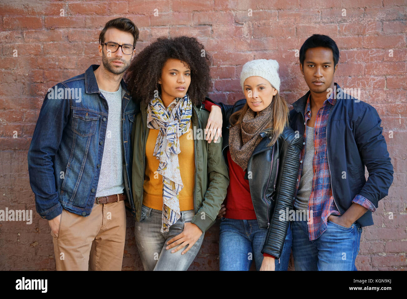 Trendy people standing in front of brick wall Stock Photo - Alamy