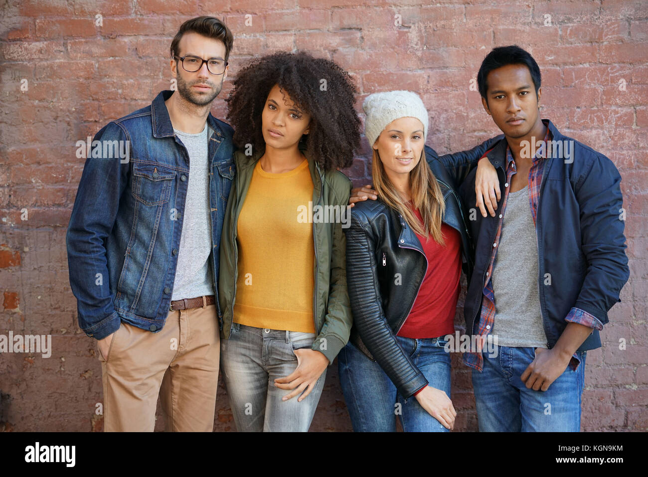 Trendy people standing in front of brick wall Stock Photo - Alamy