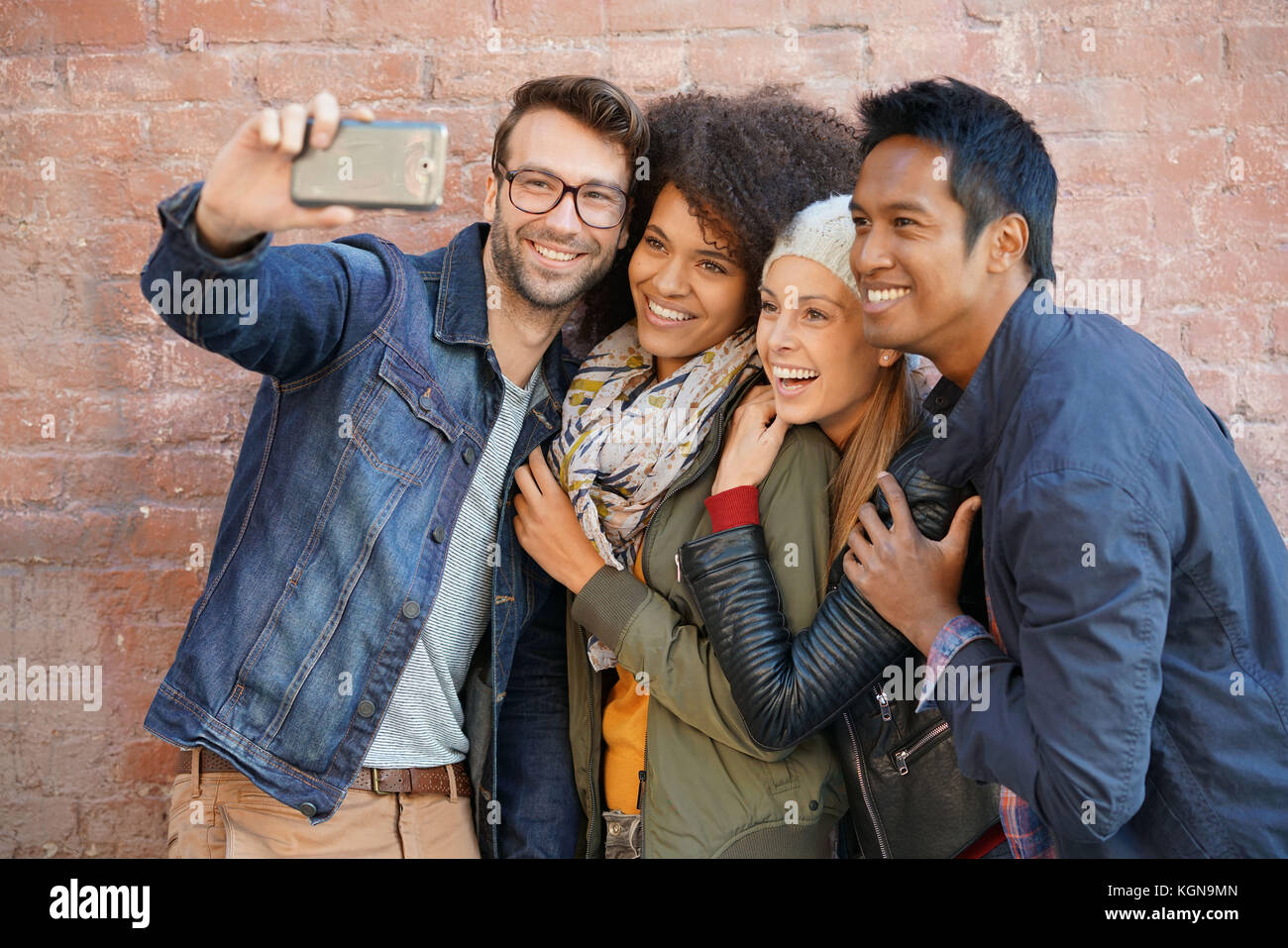 Group of trendy people taking selfie picture, brick wall background ...