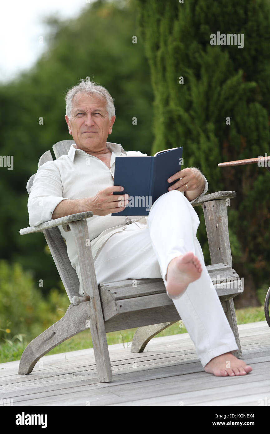 Senior man reading book in pool deck chair Stock Photo - Alamy
