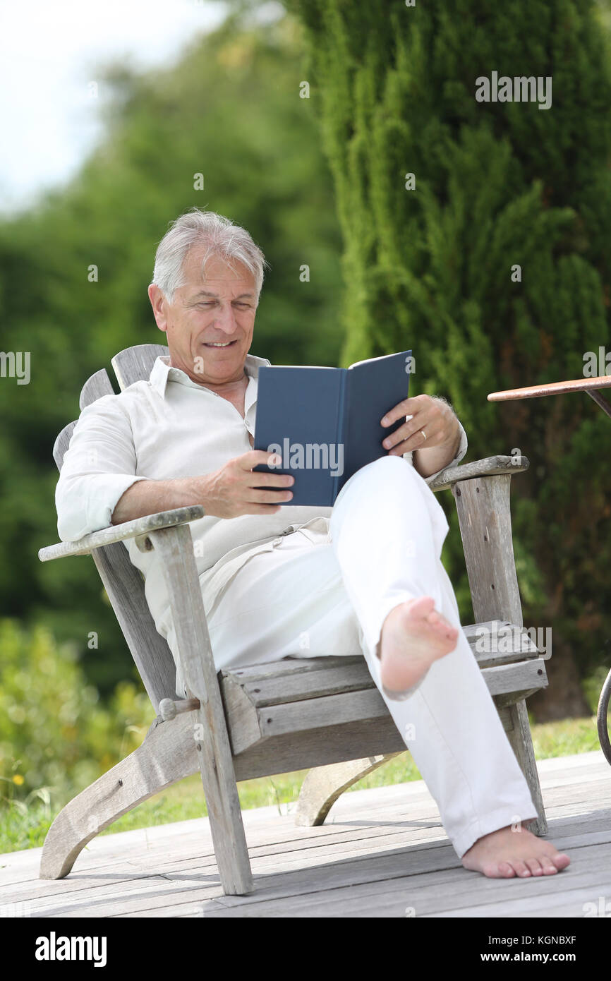 Senior man reading book in pool deck chair Stock Photo - Alamy