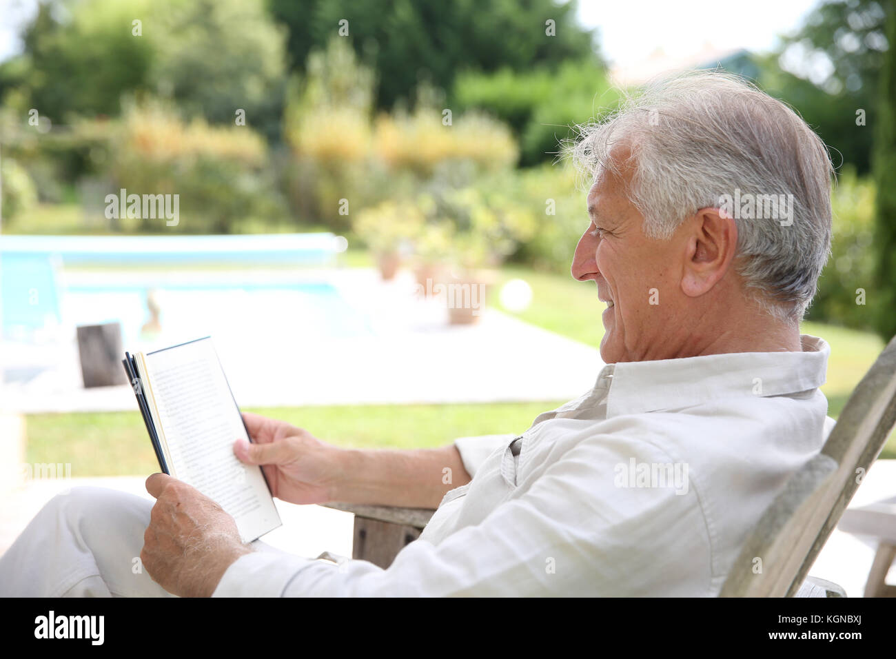 Senior man reading book in pool deck chair Stock Photo - Alamy